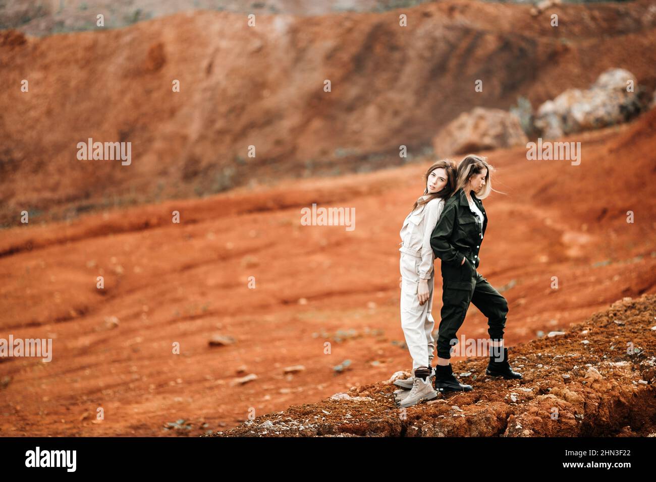 Girls in a post-apocalyptic place, a quarry with red earth and stones ...