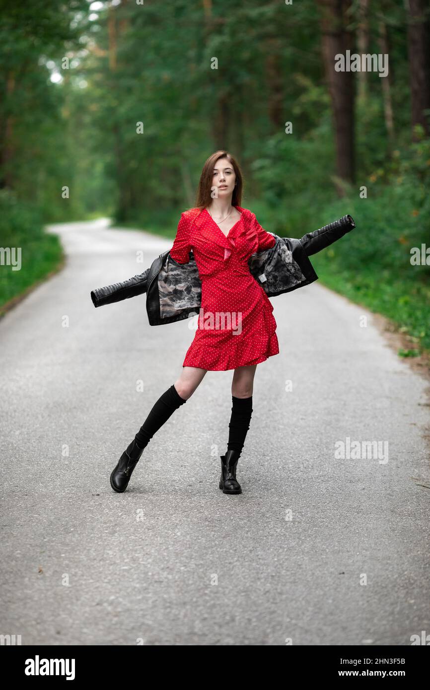 A girl in a light red airy dress, a leather jacket in a rockstyle on an ...