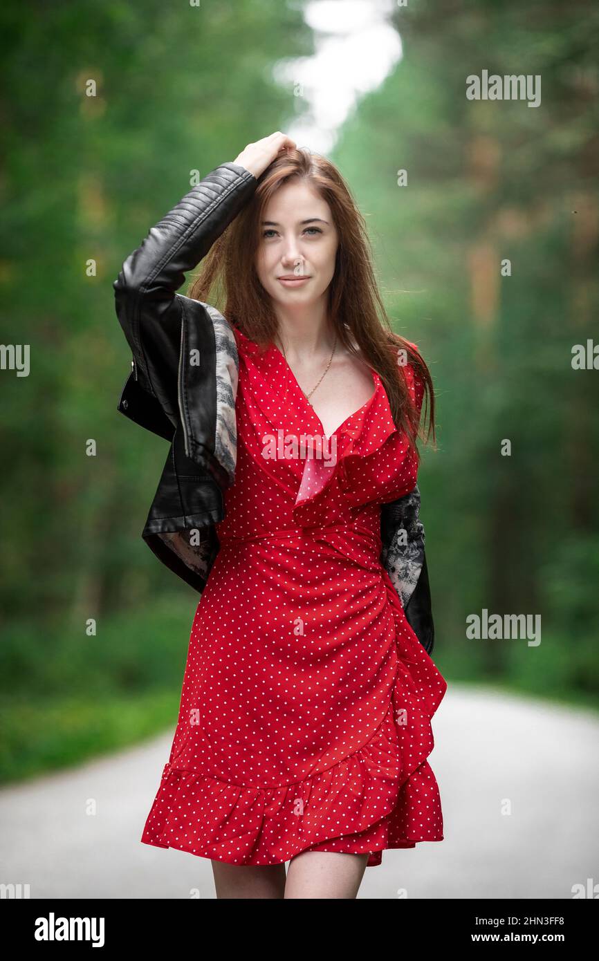A girl in a light red airy dress, a leather jacket in a rockstyle on an ...