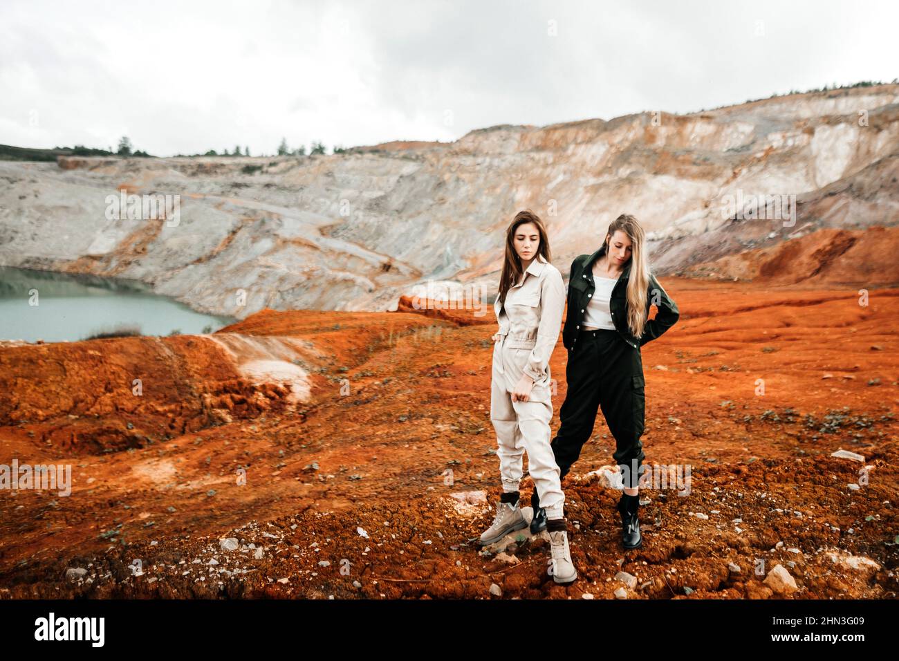 Girls in a post-apocalyptic place, a quarry with red earth and stones ...