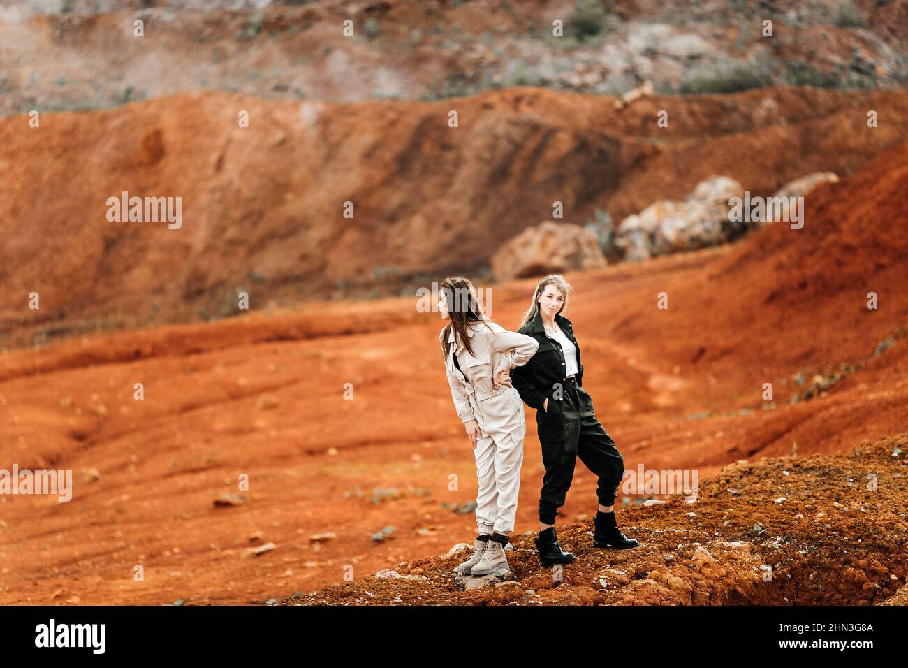 Girls in a post-apocalyptic place, a quarry with red earth and stones ...