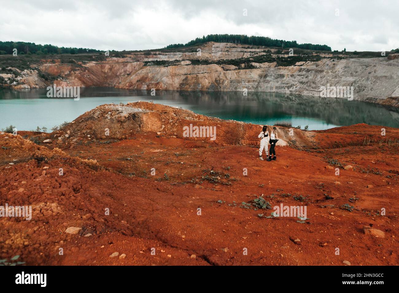 Girls in a post-apocalyptic place, a quarry with red earth and stones ...