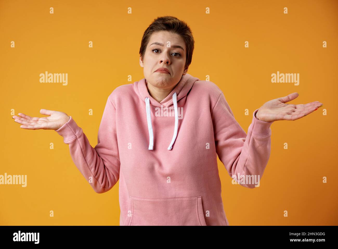 Studio portrait of awkward young woman feeling confused and puzzled ...