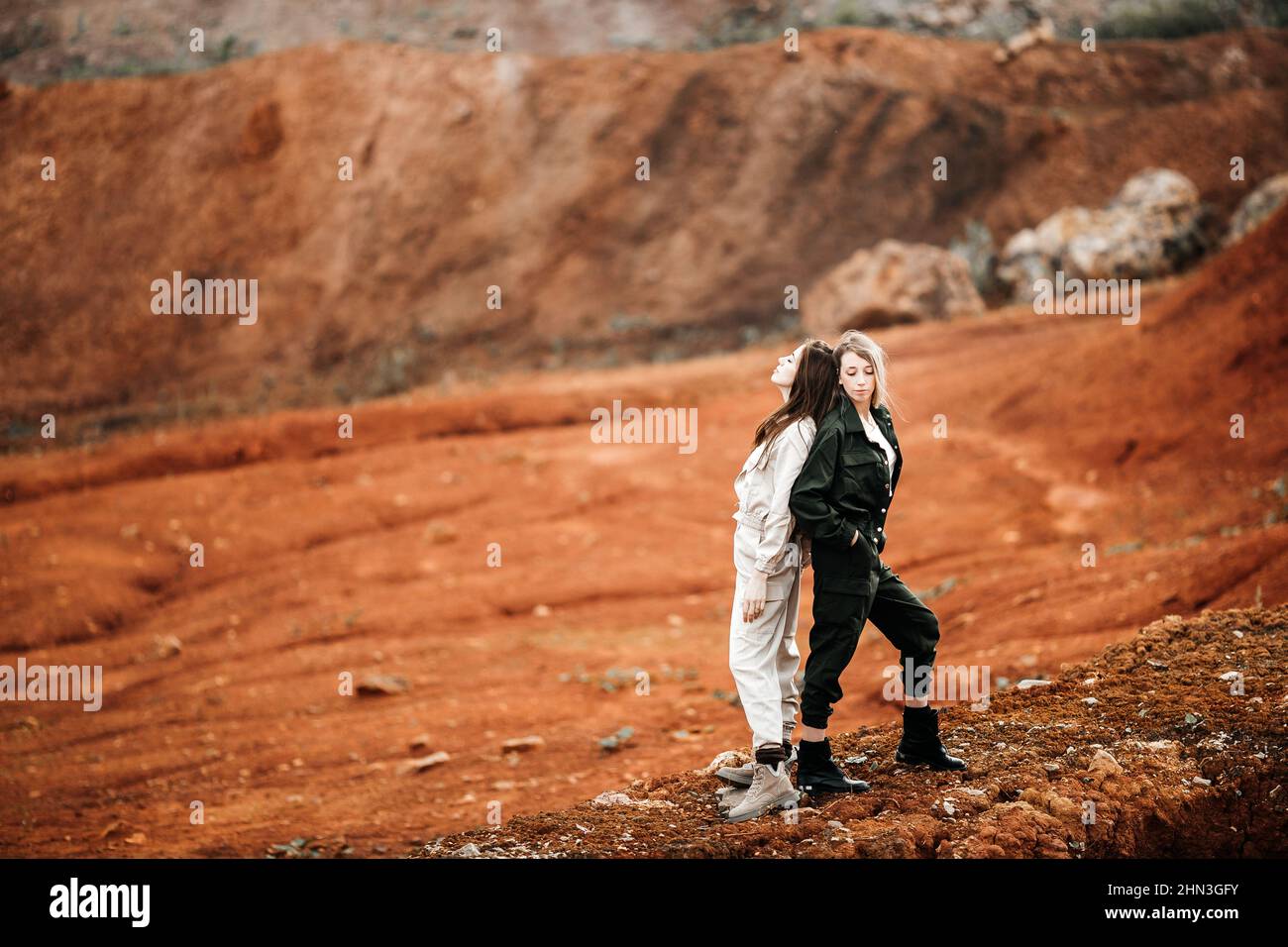 Girls in a post-apocalyptic place, a quarry with red earth and stones ...