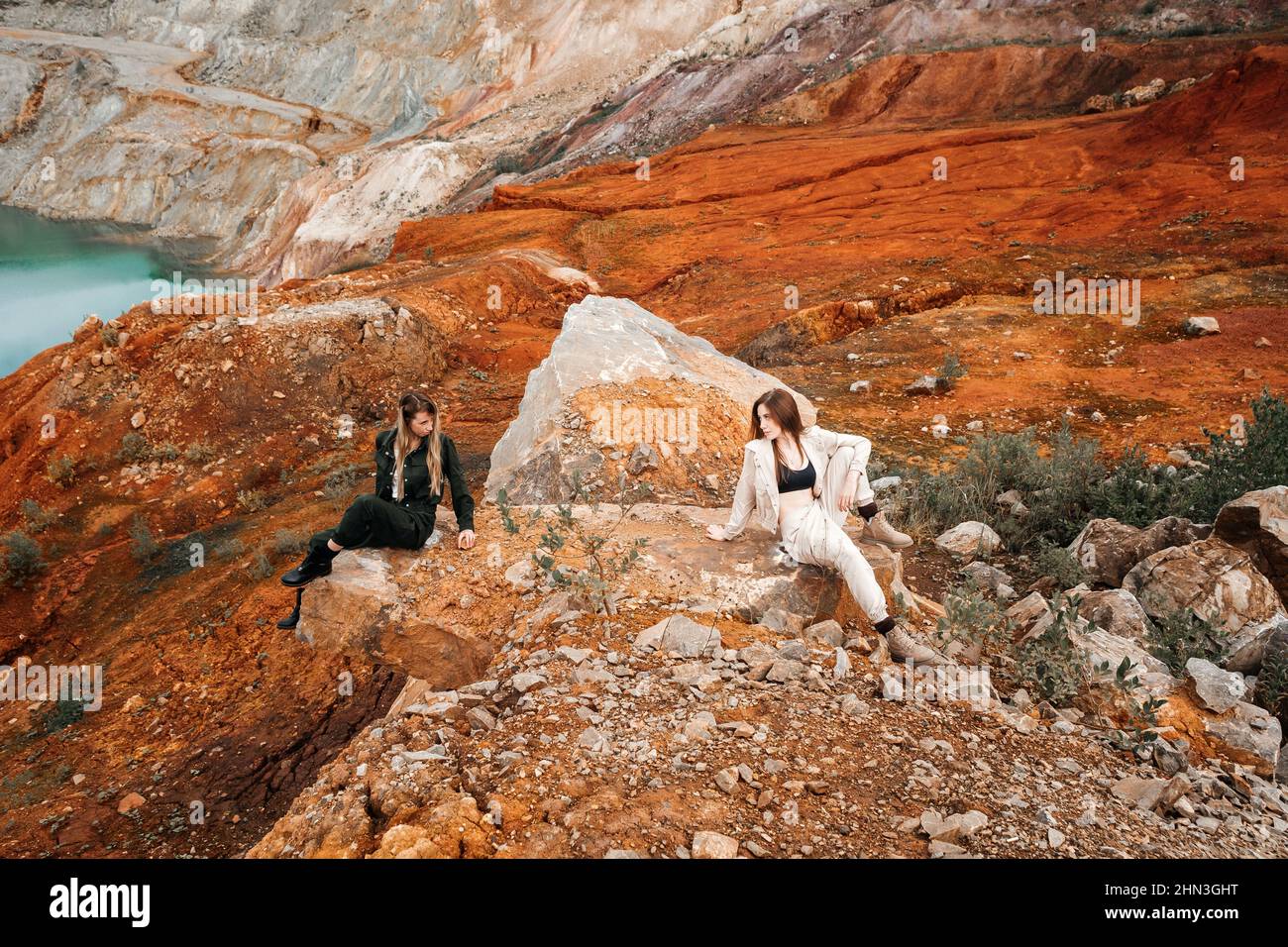 Girls in a post-apocalyptic place, a quarry with red earth and stones ...