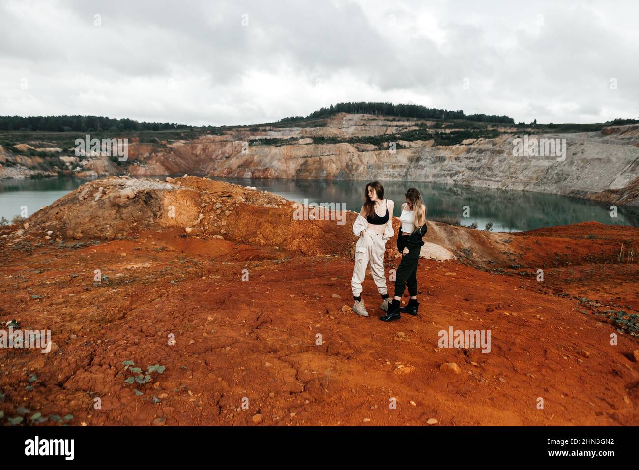 Girls in a post-apocalyptic place, a quarry with red earth and stones ...