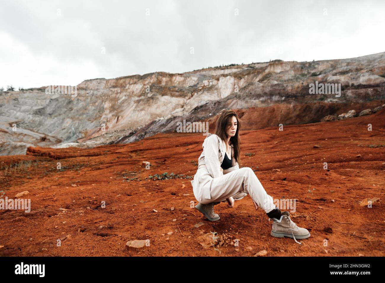 Girls in a post-apocalyptic place, a quarry with red earth and stones ...