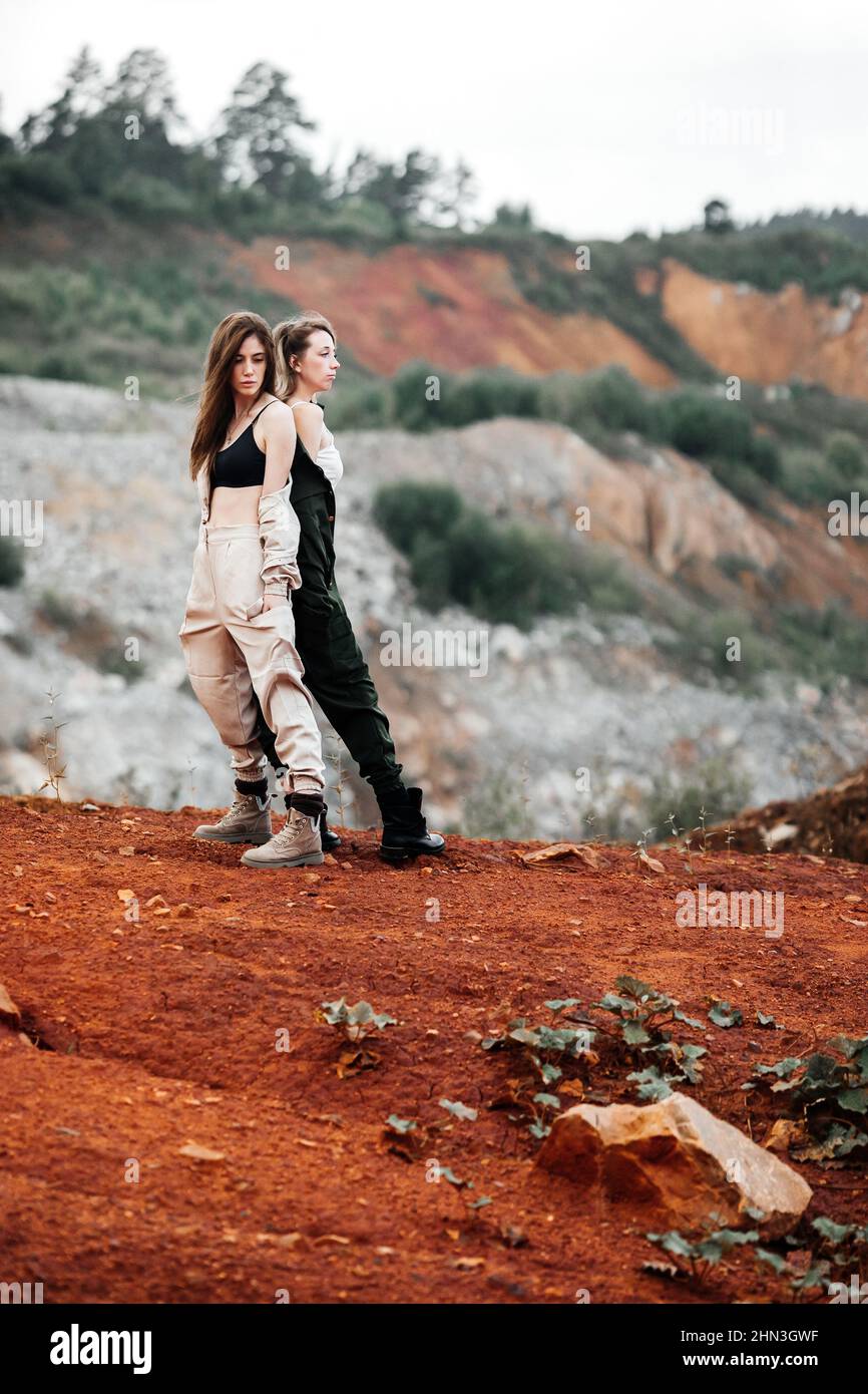 Girls in a post-apocalyptic place, a quarry with red earth and stones ...