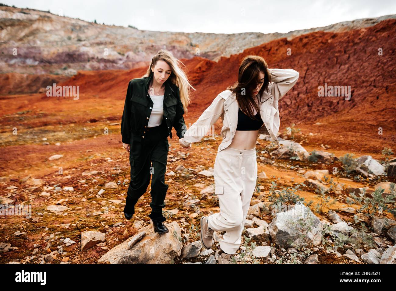 Girls in a post-apocalyptic place, a quarry with red earth and stones ...