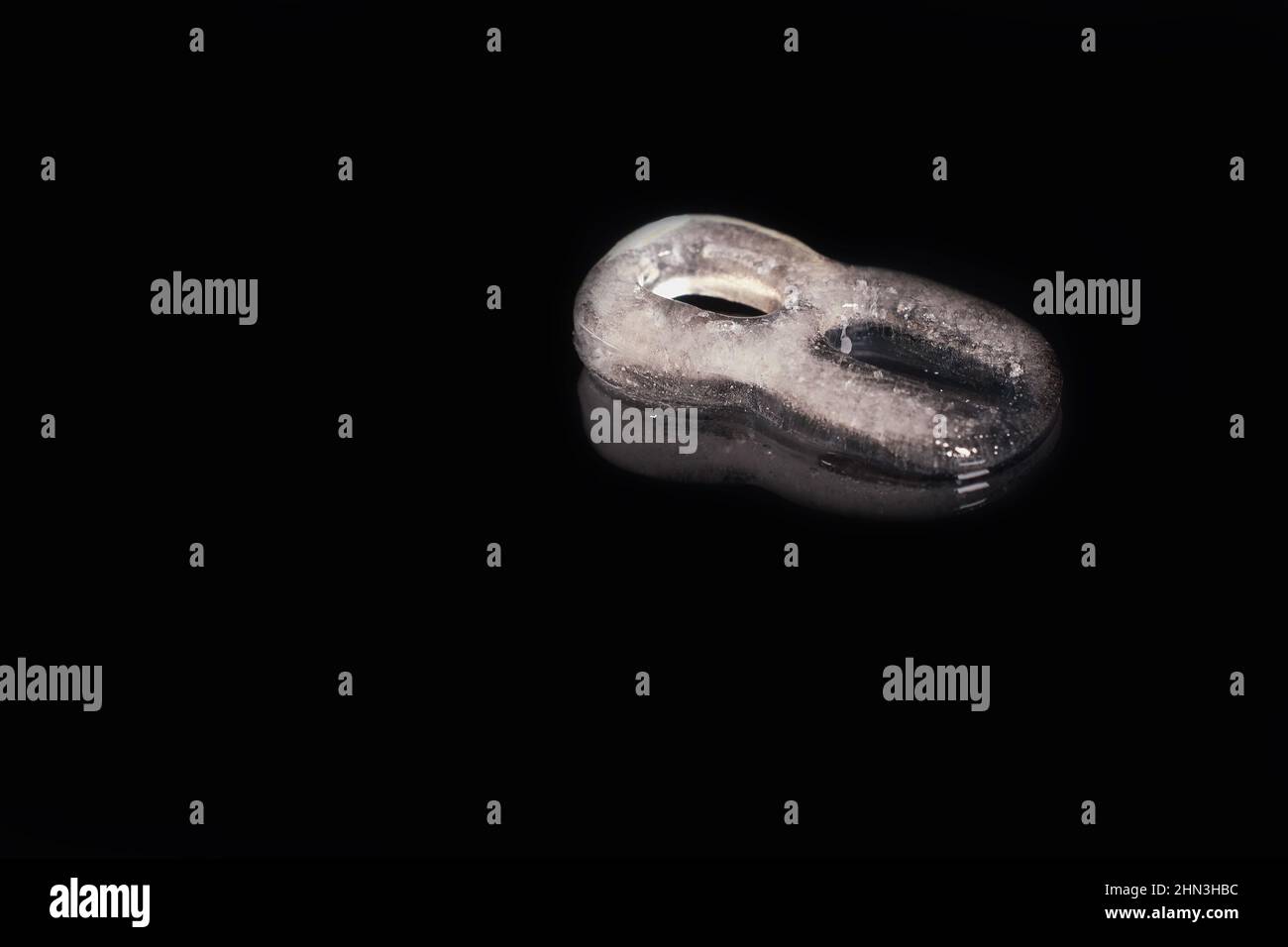 A melted ice figure Eight on a black background with a reflection Stock ...