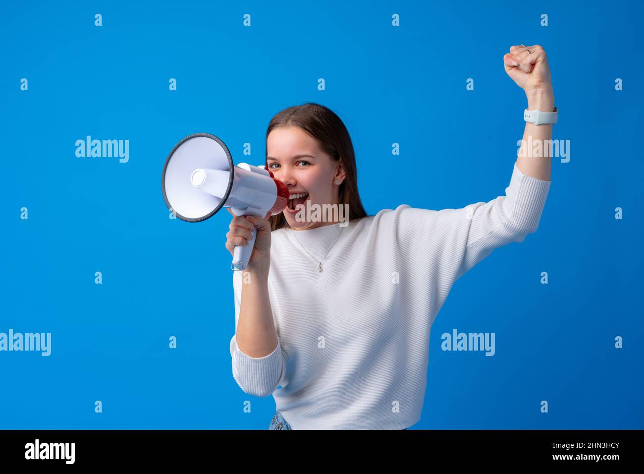 Teen girl making announcement with megaphone at blue studio Stock Photo ...