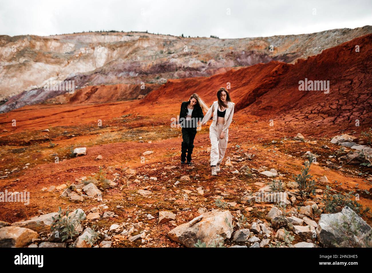 Girls in a post-apocalyptic place, a quarry with red earth and stones in work clothes Stock ...