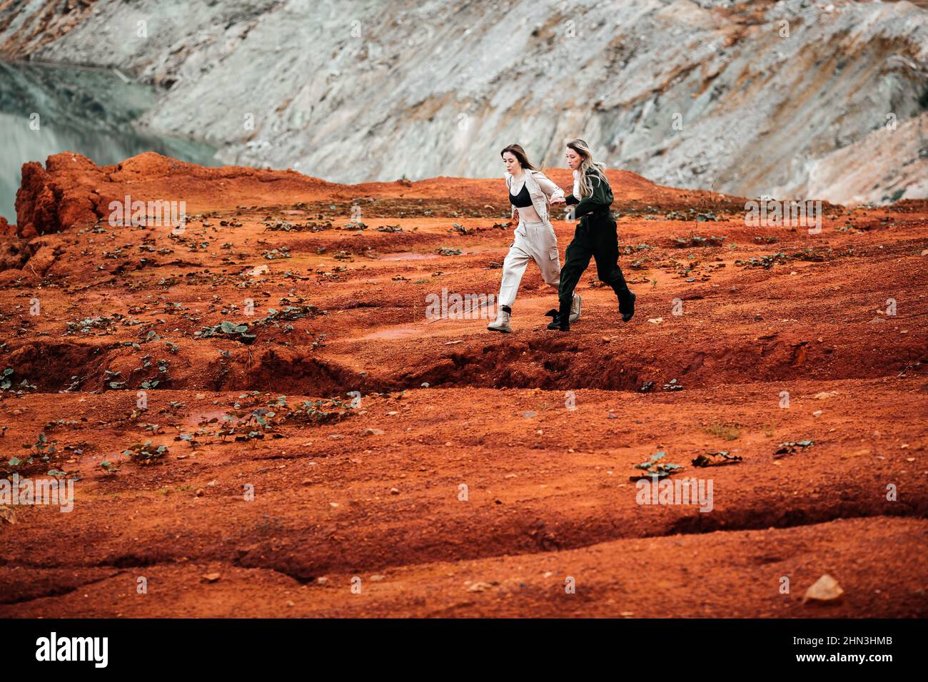 Girls in a post-apocalyptic place, a quarry with red earth and stones ...
