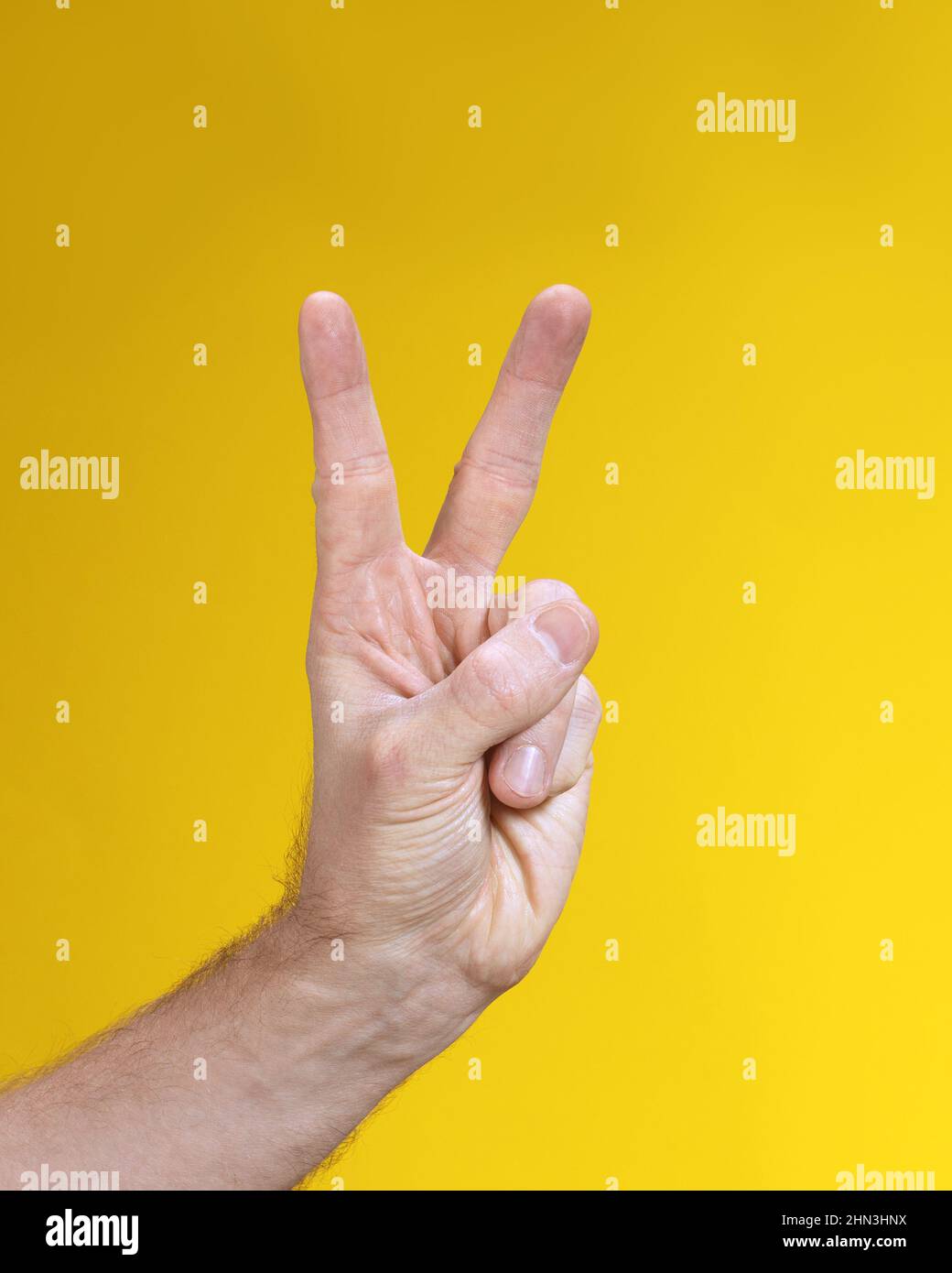 Male two fingers up on hand gesture isolated on yellow background ...
