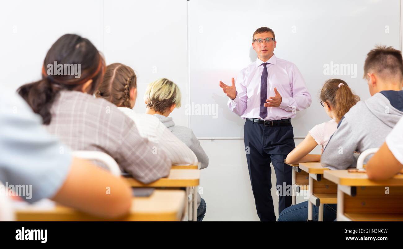 Adult teacher is giving lecture for students in class Stock Photo - Alamy