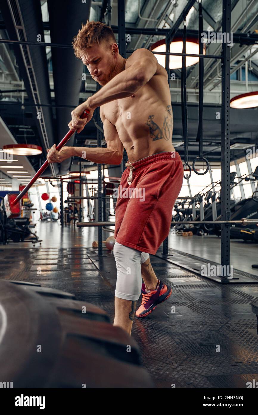 Man fitness training with large and heavy tire hits hammer. Concept ...