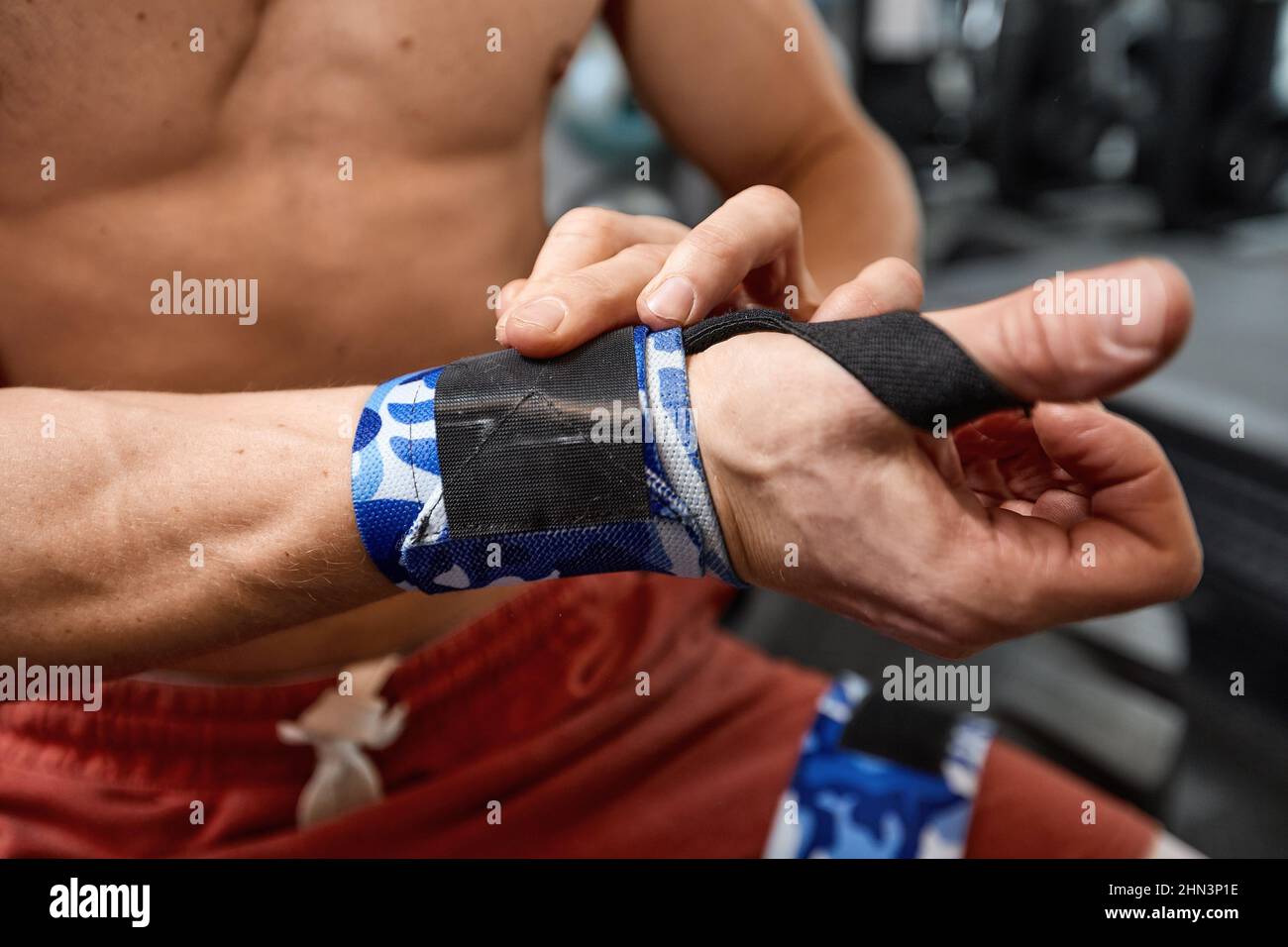 A beautiful athlete boxer, wraps his hands on sports bandages for ...