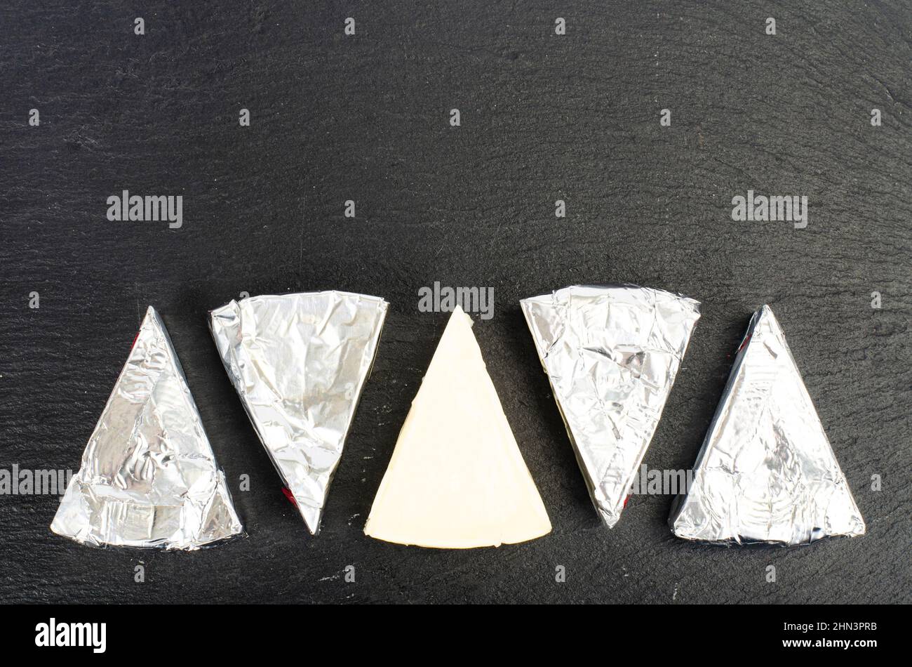 Cheese triangles in foil on black. Studio Photo Stock Photo - Alamy