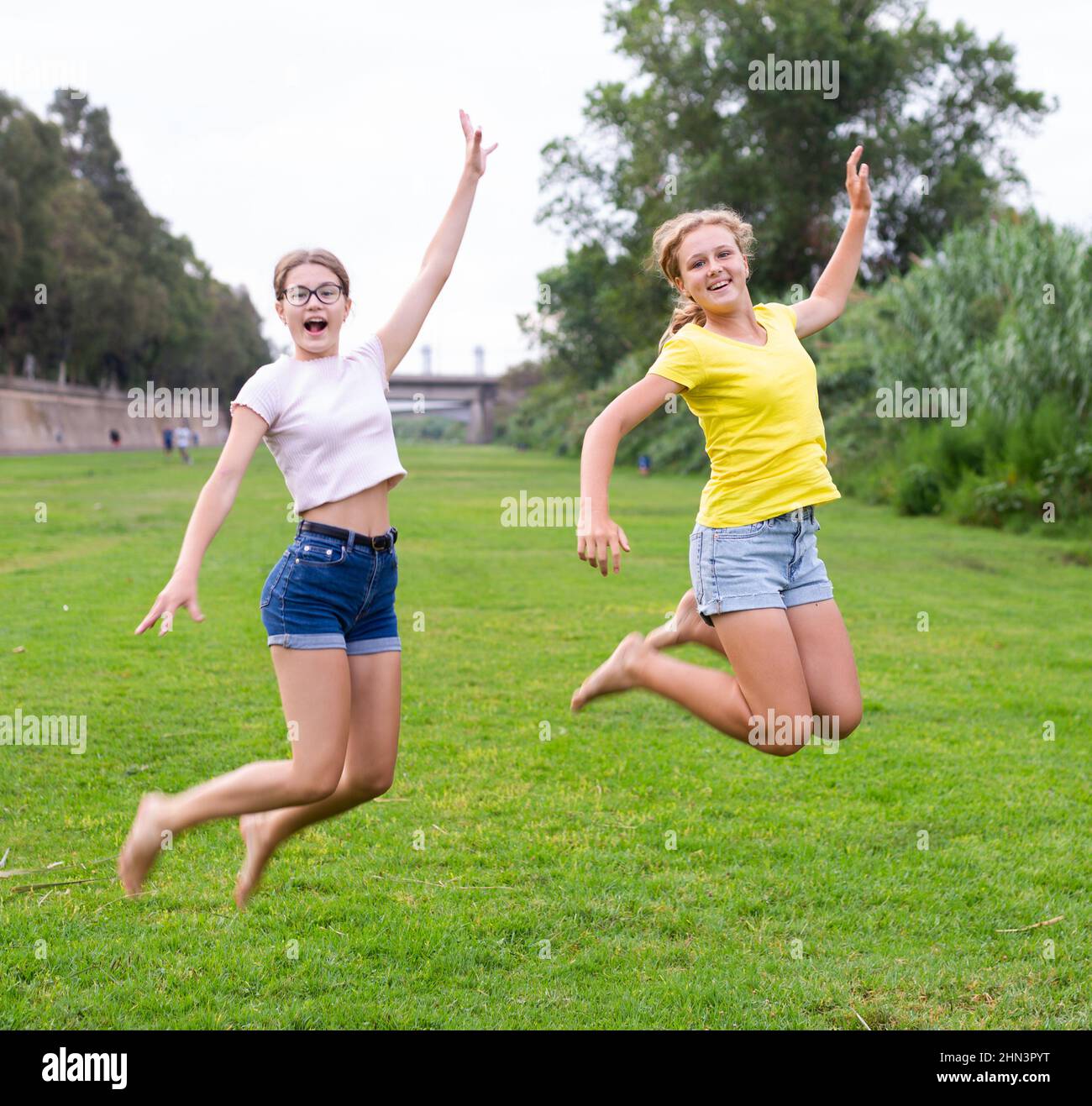 Two young barefoot girls jumping on grass Stock Photo - Alamy