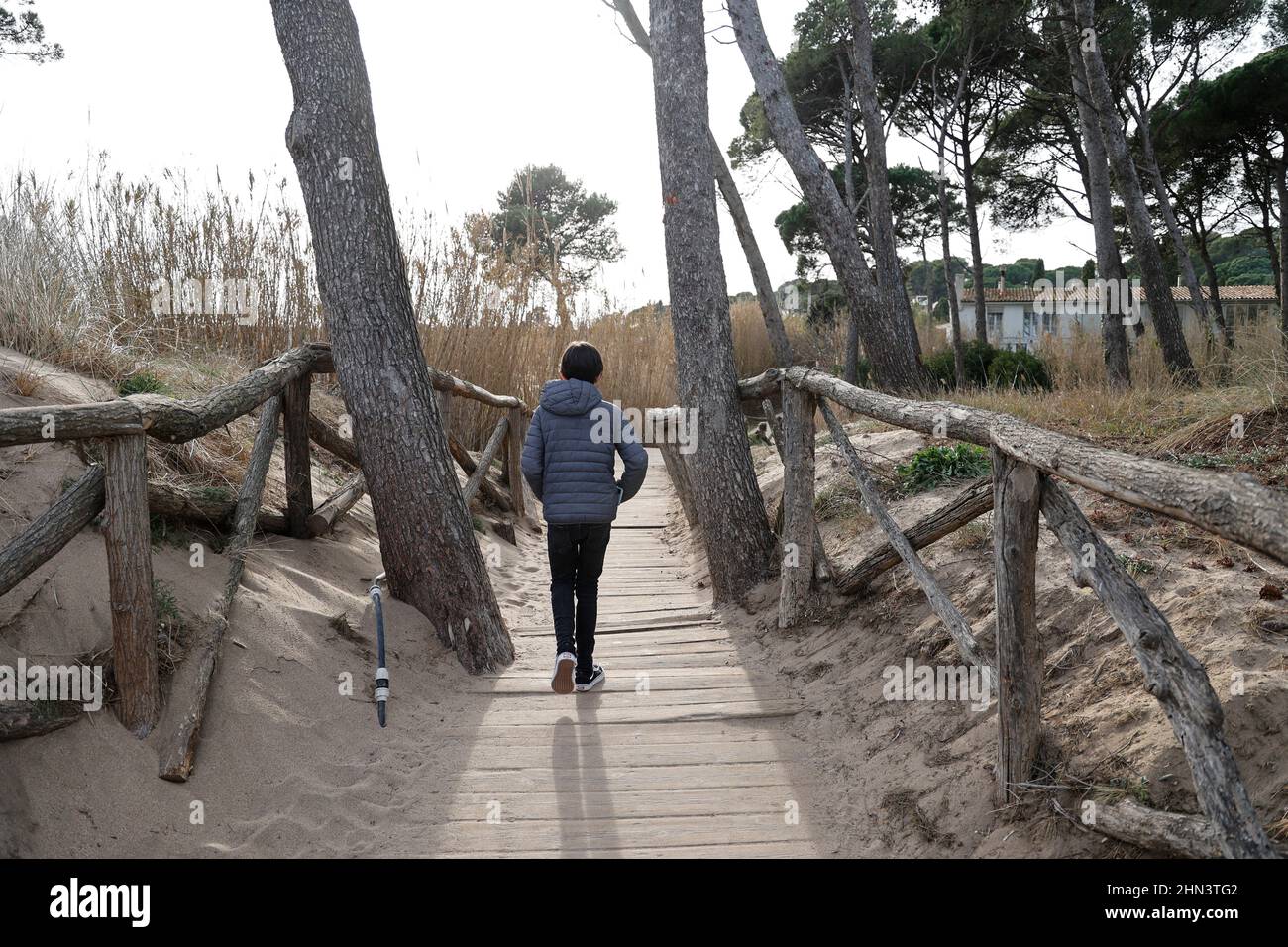 Boy walking alone along a path by the sea Stock Photo - Alamy