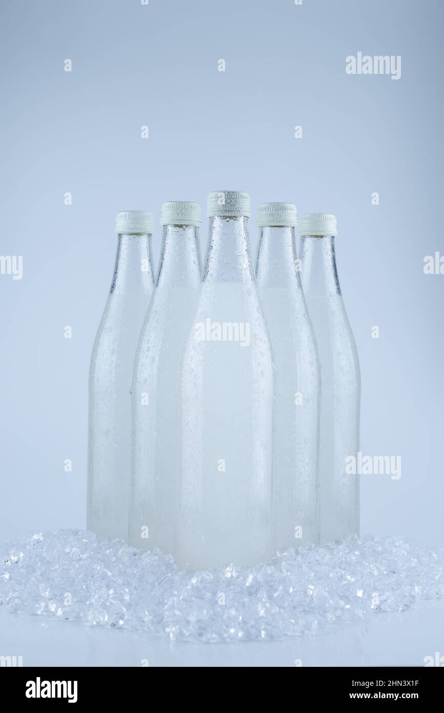 A white bottle with a soda drink on ice isolated on a white background ...