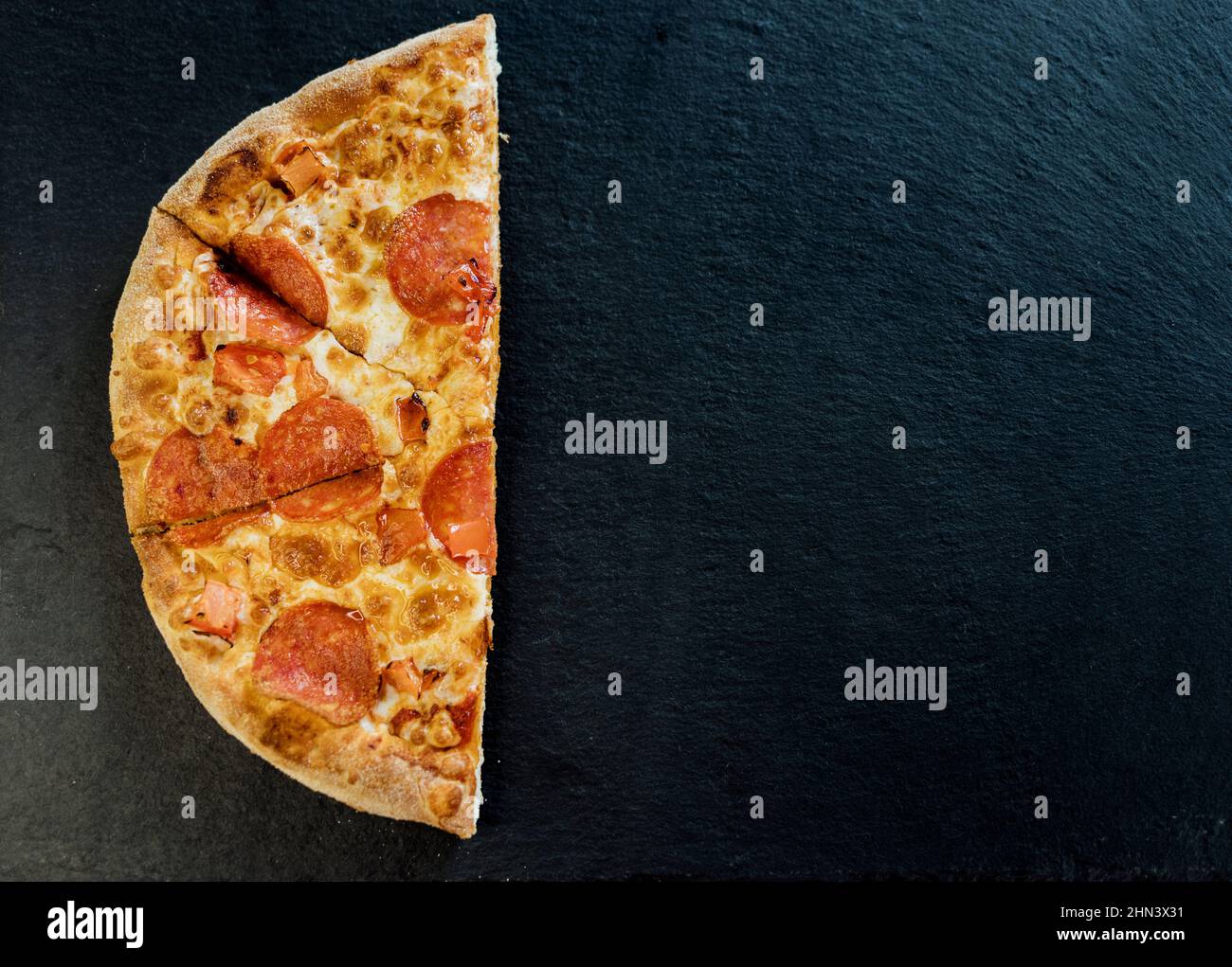 Delicious pepperoni pizza on a black concrete background. Top view of ...