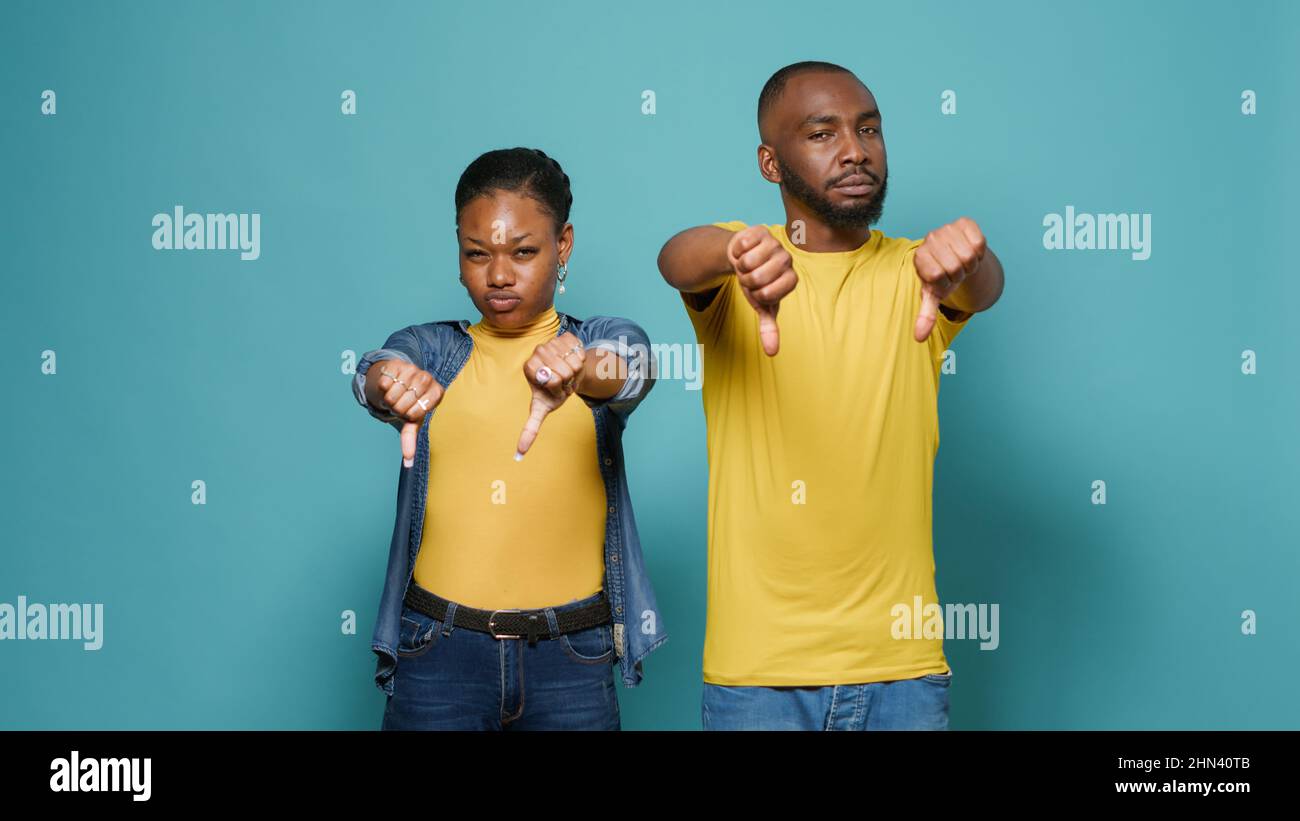 Disappointed people doing thumbs down gesture on studio camera. Man and ...