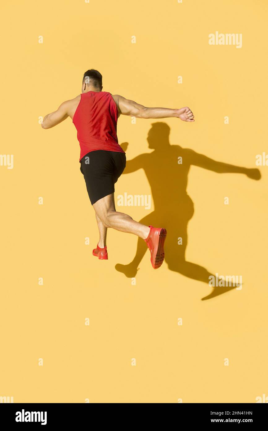 Man in red with shadow running on yellow background Stock Photo - Alamy