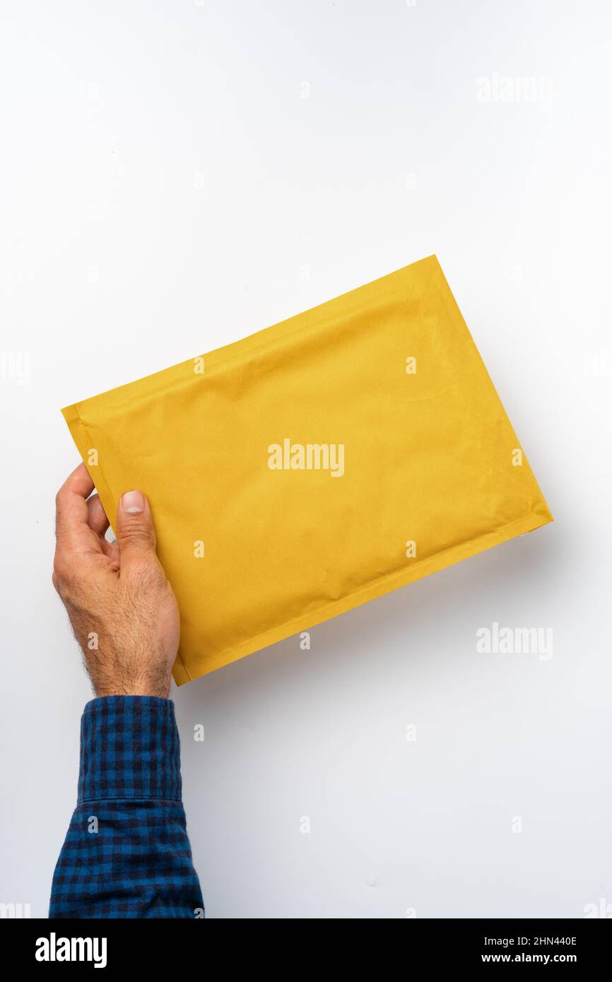 Male hand holding parcel post against white background Stock Photo - Alamy