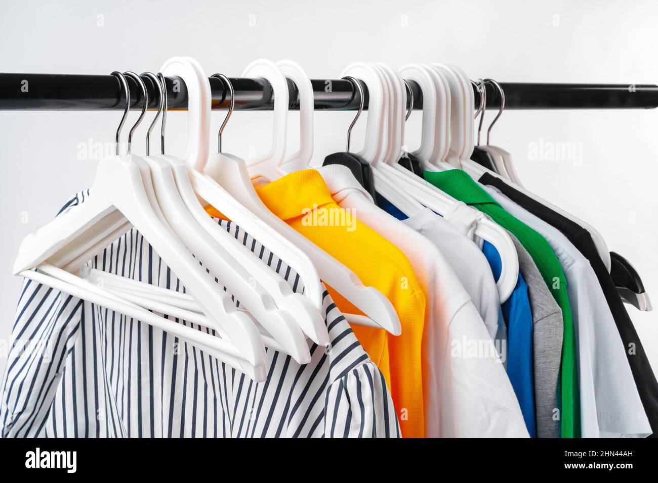 Clothes hang on clothing rack over white background Stock Photo - Alamy