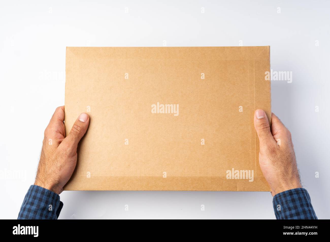 Male hand holding parcel post against white background Stock Photo - Alamy