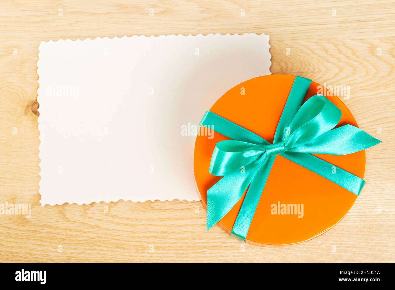 Orange gift box with blank gift tag on wooden background Stock Photo ...