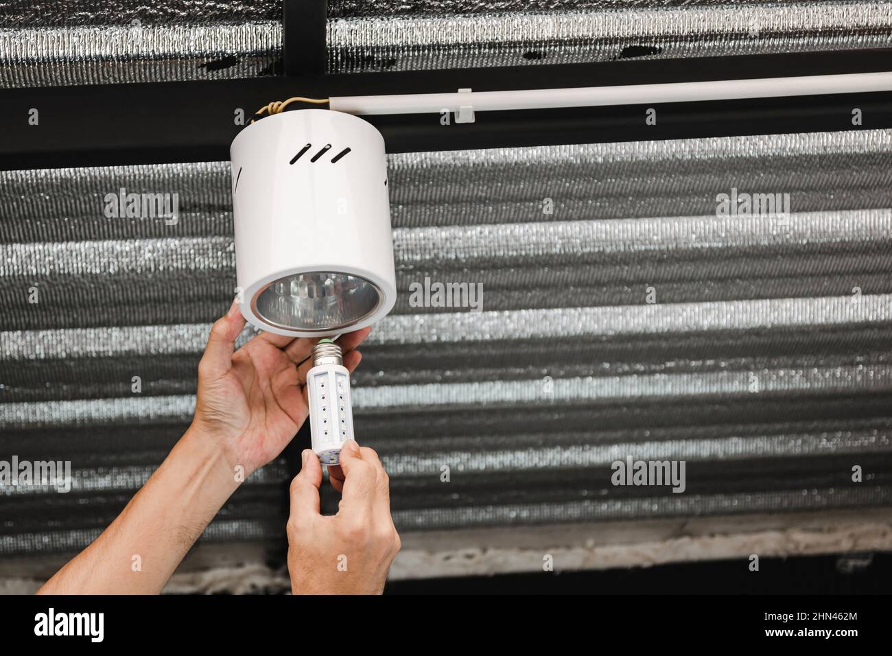 Close up human hand is installing an LED light bulb in a circular ...