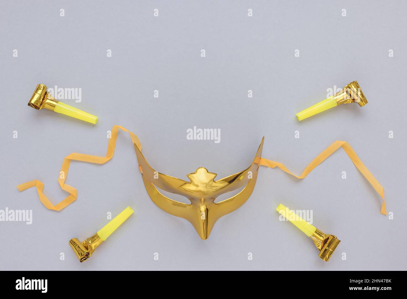 Gold carnival mask on festive gray with party pipes background ...