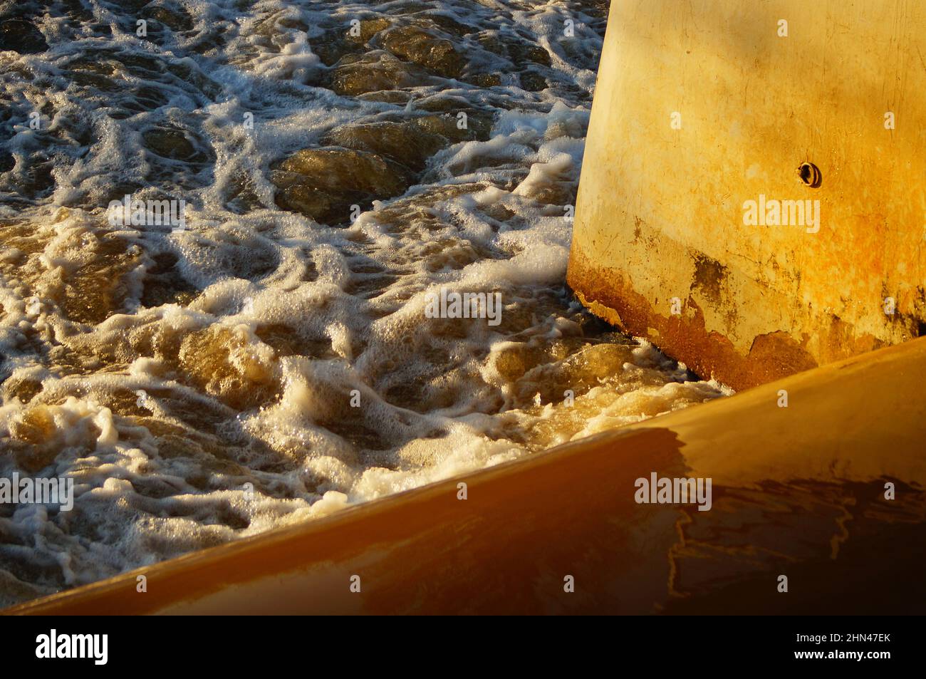 The river Nidda flows over the weir in Praunheim in the evening light ...