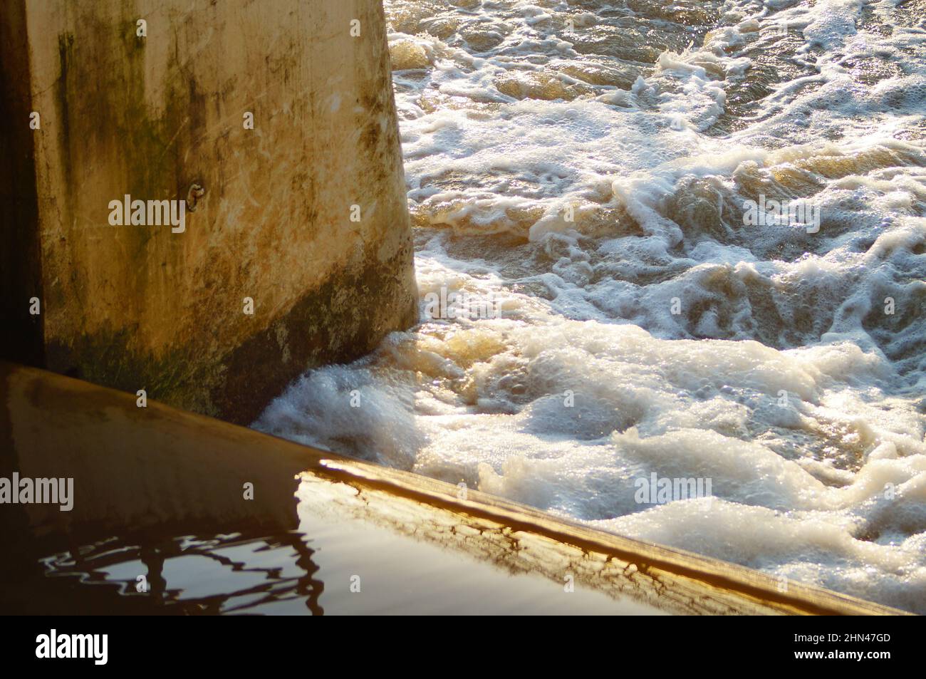 The river Nidda flows over the weir in Praunheim in the evening light ...