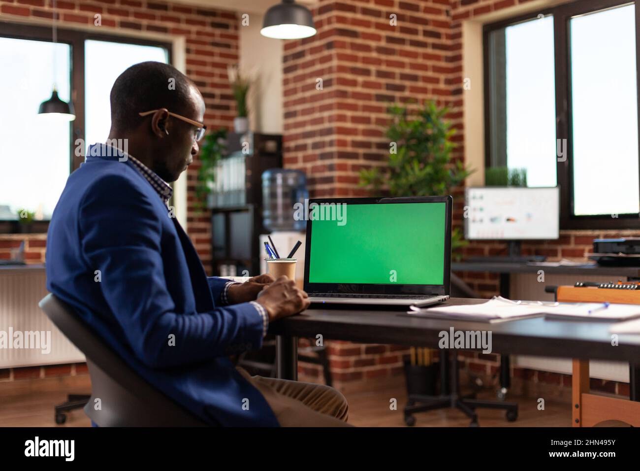 Entrepreneur using laptop with horizontal green screen to work on ...