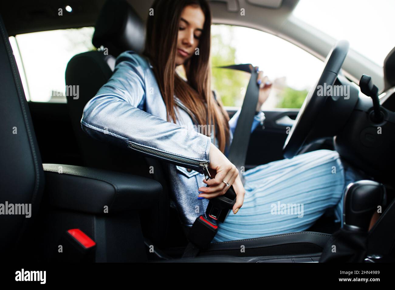 Gorgeous woman sitting inside car interior and tie belt Stock Photo - Alamy