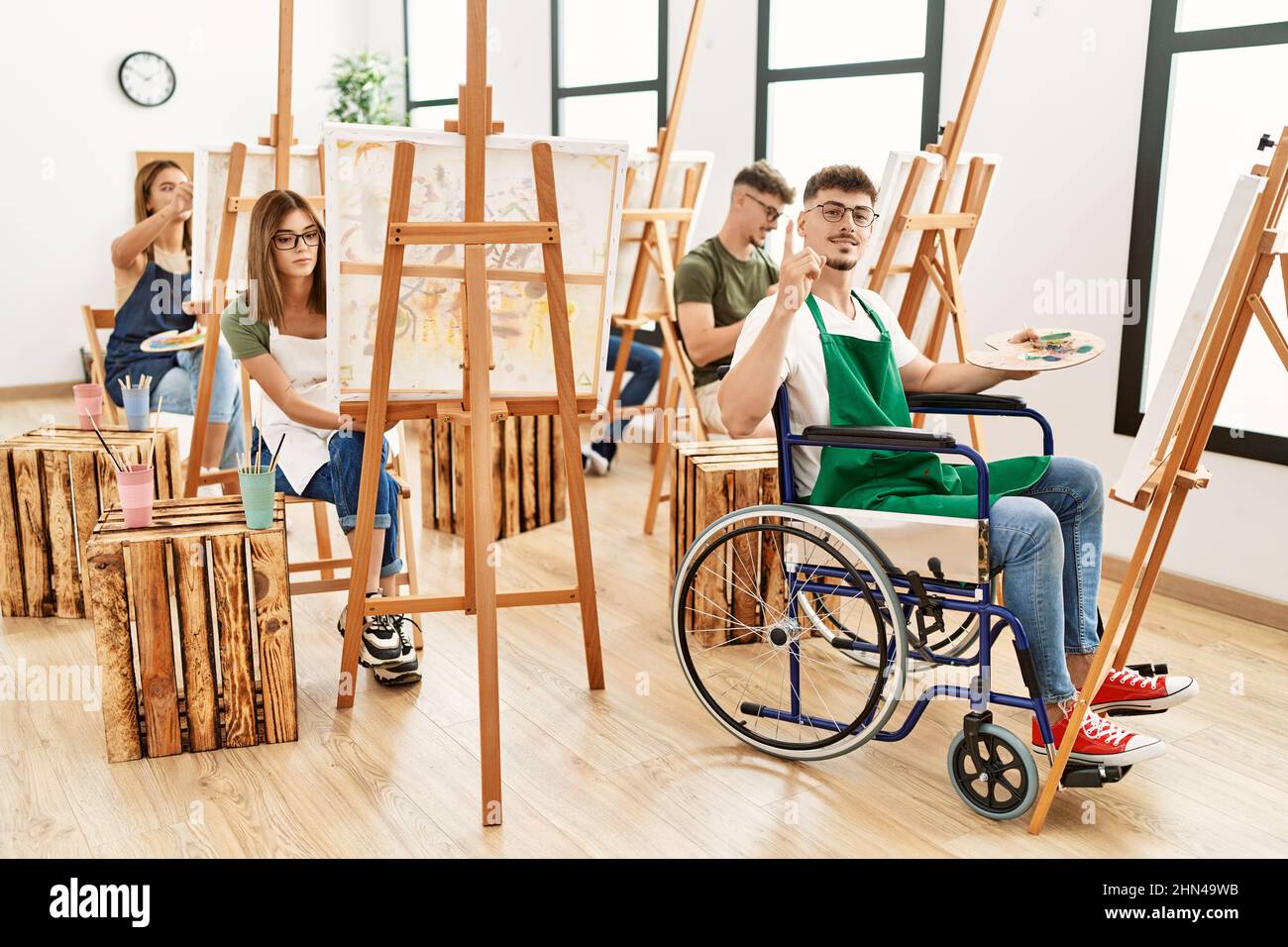 Young disabled man sitting on wheelchair drawing at art studio ...