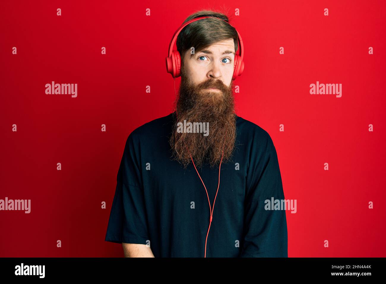 Redhead Man With Long Beard Listening To Music Using Headphones Relaxed