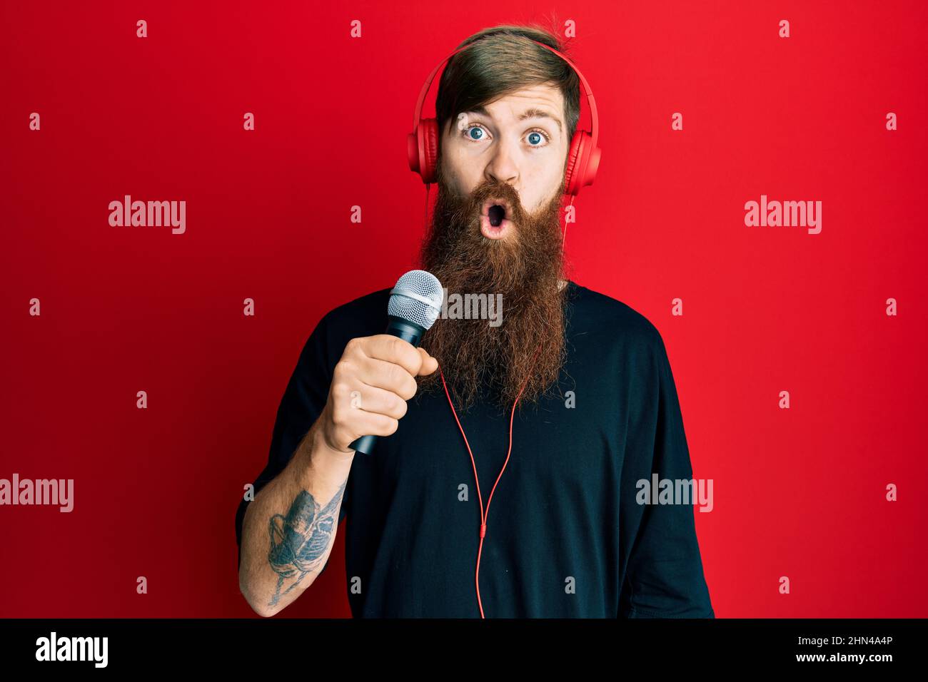 Redhead man with long beard singing song using microphone and wearing ...