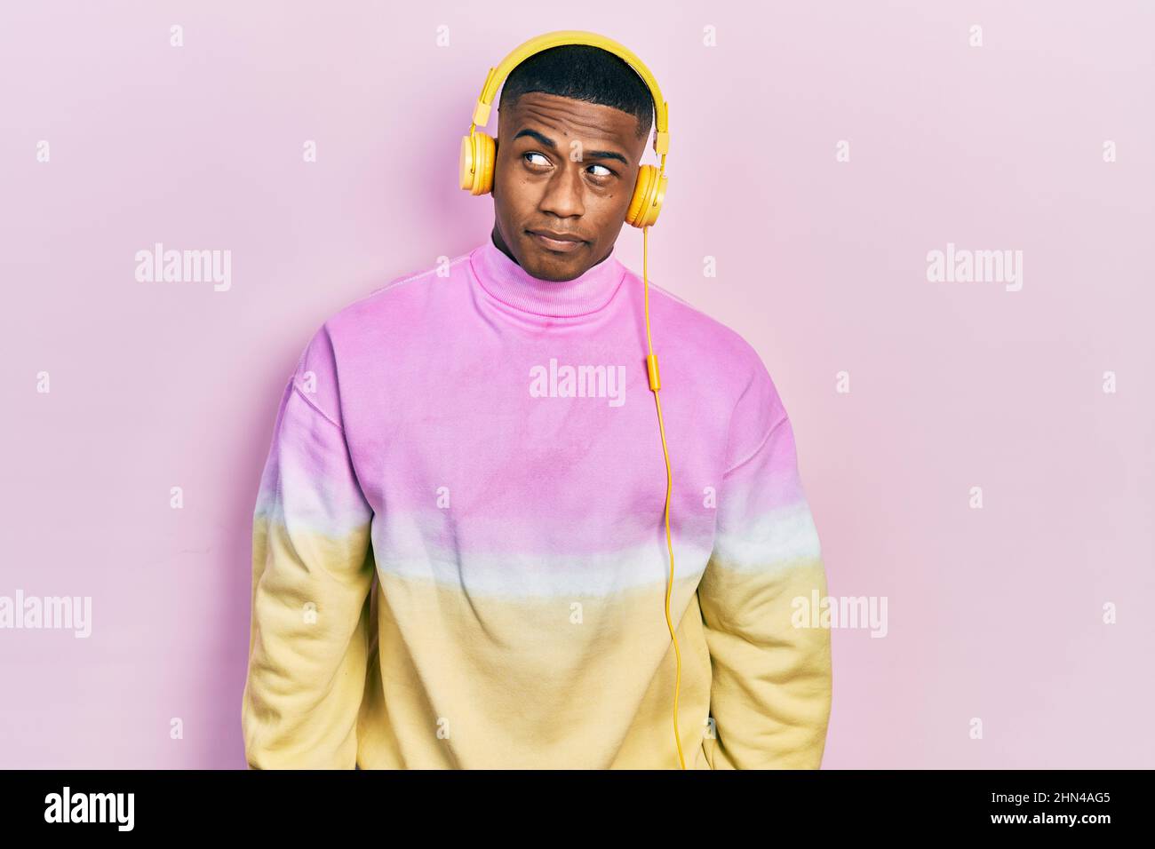 Young black man listening to music wearing headphones smiling looking ...