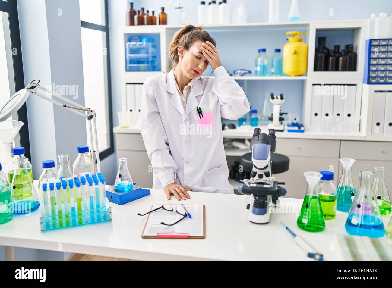 Young woman wearing scientist uniform stressed working at laboratory ...