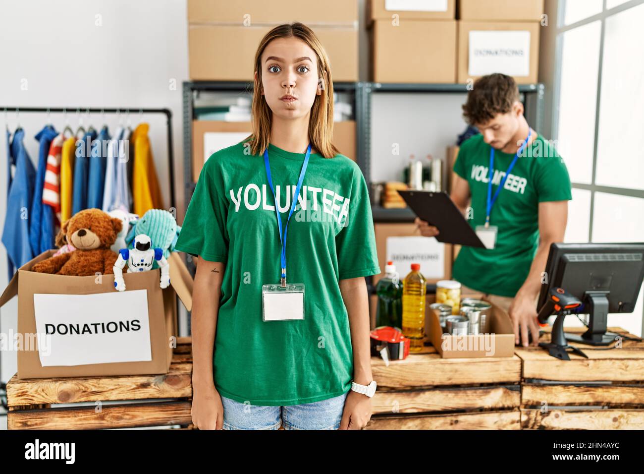 Young blonde girl wearing volunteer t shirt at donation stand puffing ...
