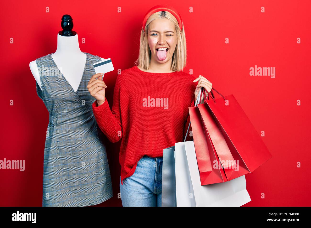 Beautiful blonde woman holding shopping bags and credit card sticking ...