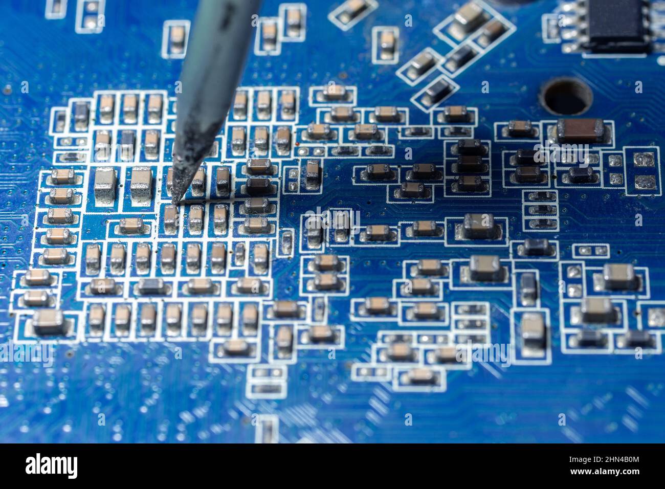 The hand holding the tin, a soldering iron solder the chip in place ...