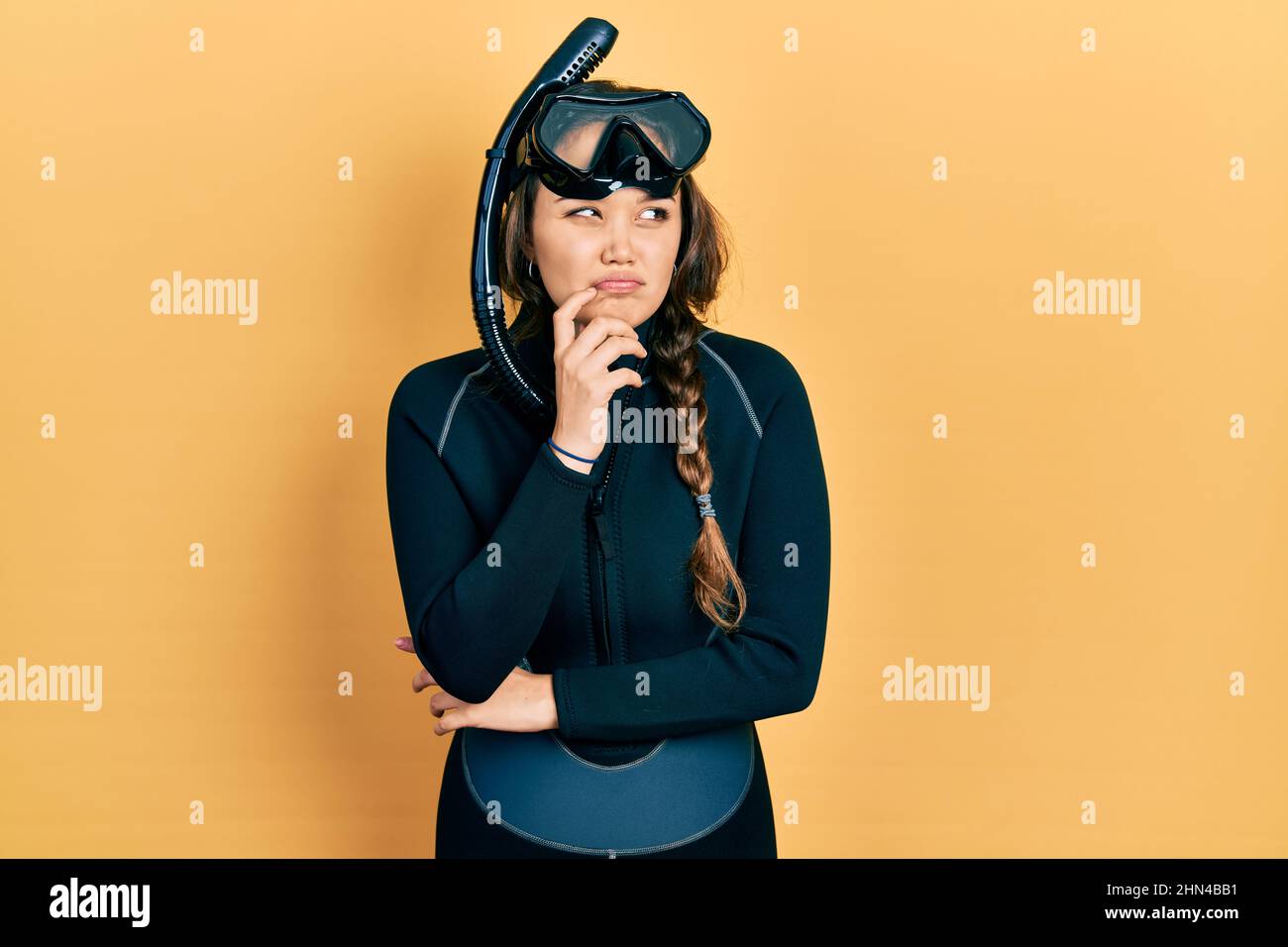 Young hispanic girl wearing diver neoprene uniform thinking ...