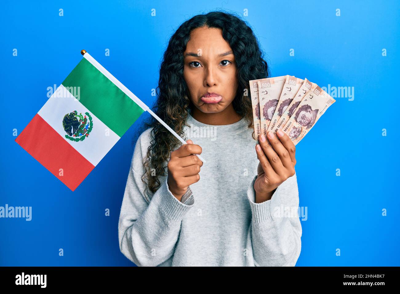 Young latin woman holding mexico flag and mexican pesos banknotes ...