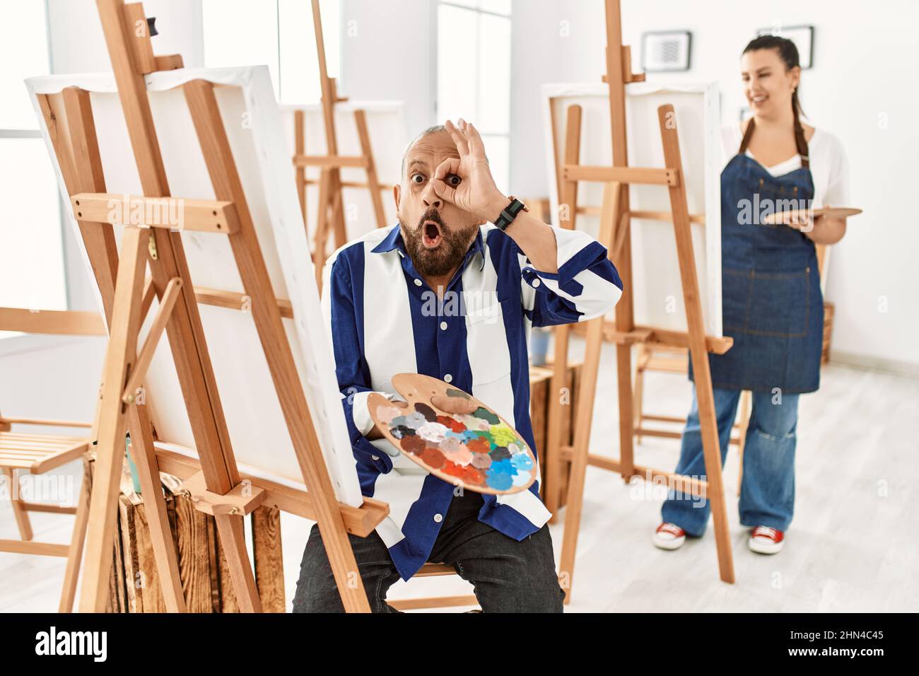 Senior artist man at art studio doing ok gesture shocked with surprised ...