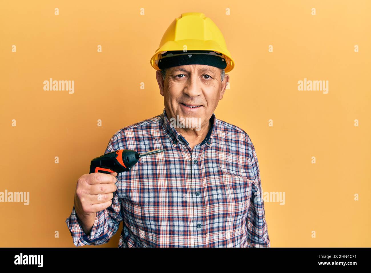 Handsome senior man with grey hair holding screwdriver wearing hardhat ...